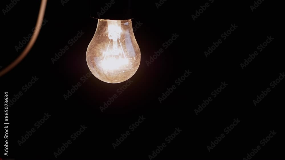 One Hanging, Glowing Light Bulb with a Wire on a Black Background. A ...