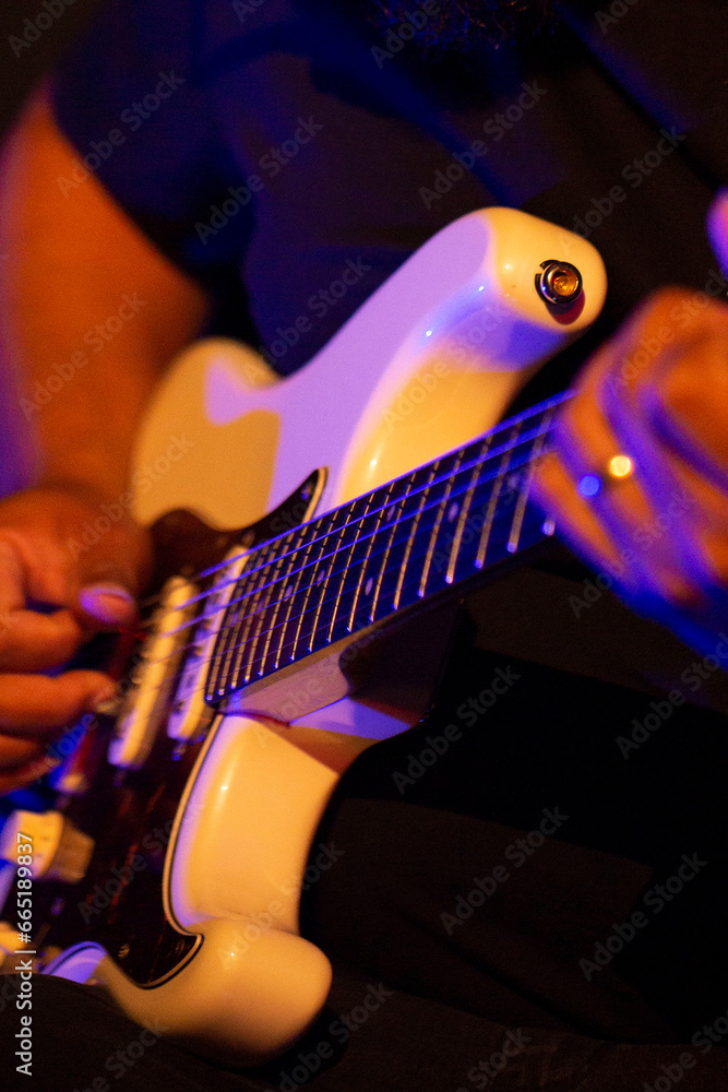 Guitarrista tocando sua guitarra branca em show com luz cenográfica de ...
