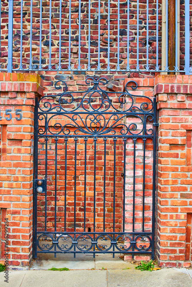 Black gate with red brick wall behind it and pillars closing off unseen ...