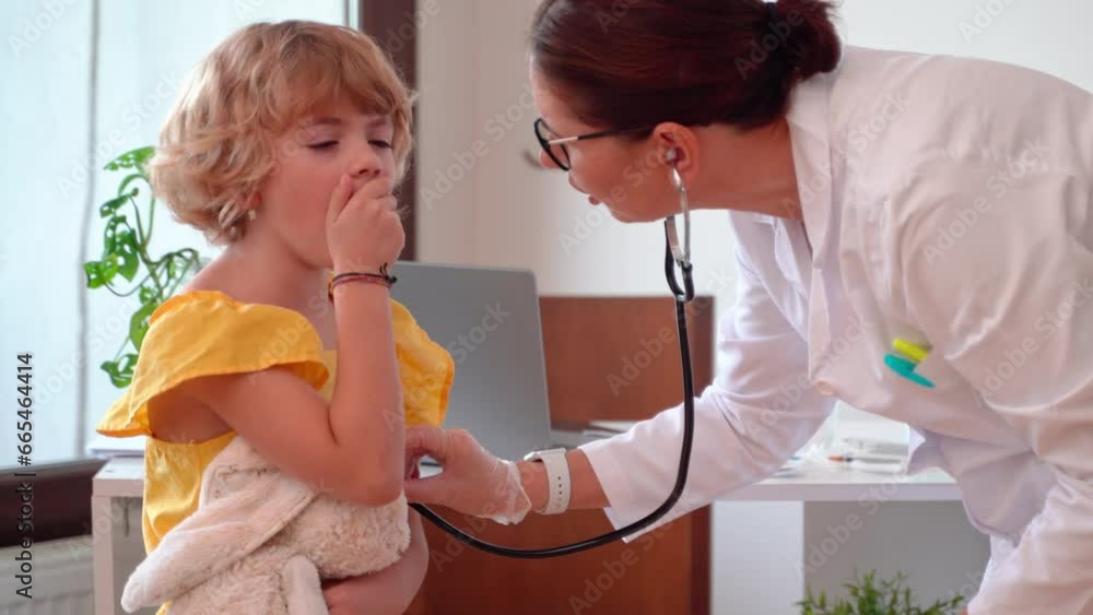 Female doctor checking child's lungs during medical checkup in medical ...