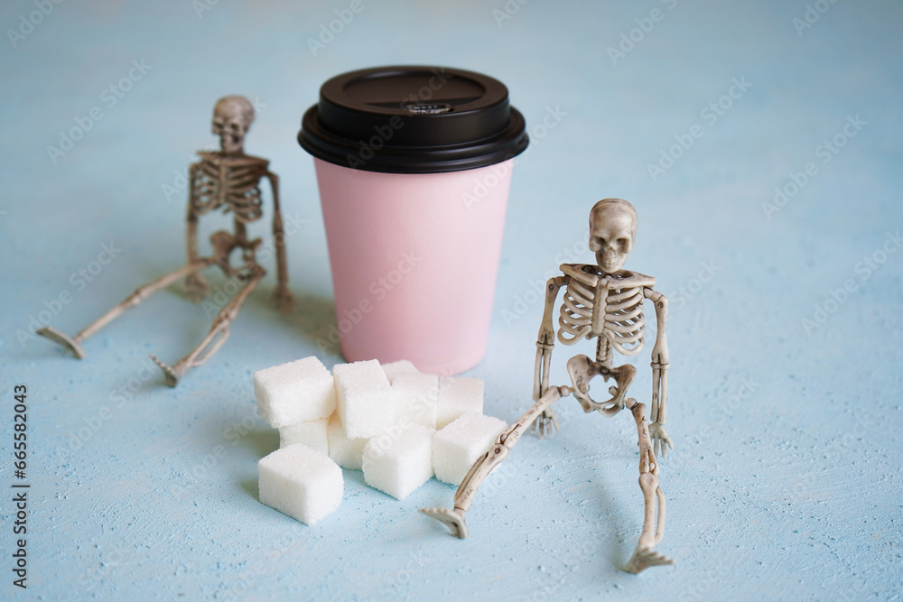 Refined sugar chunks are lying on a blue table, next to two skeletons ...