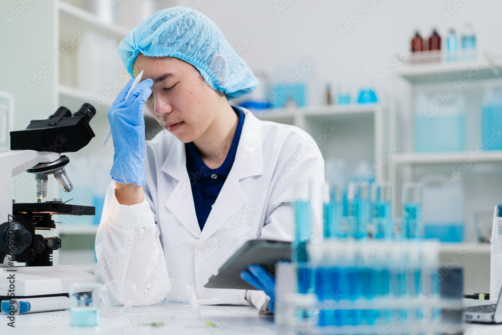 asian female scientist feeling stress and tired from working overtime ...