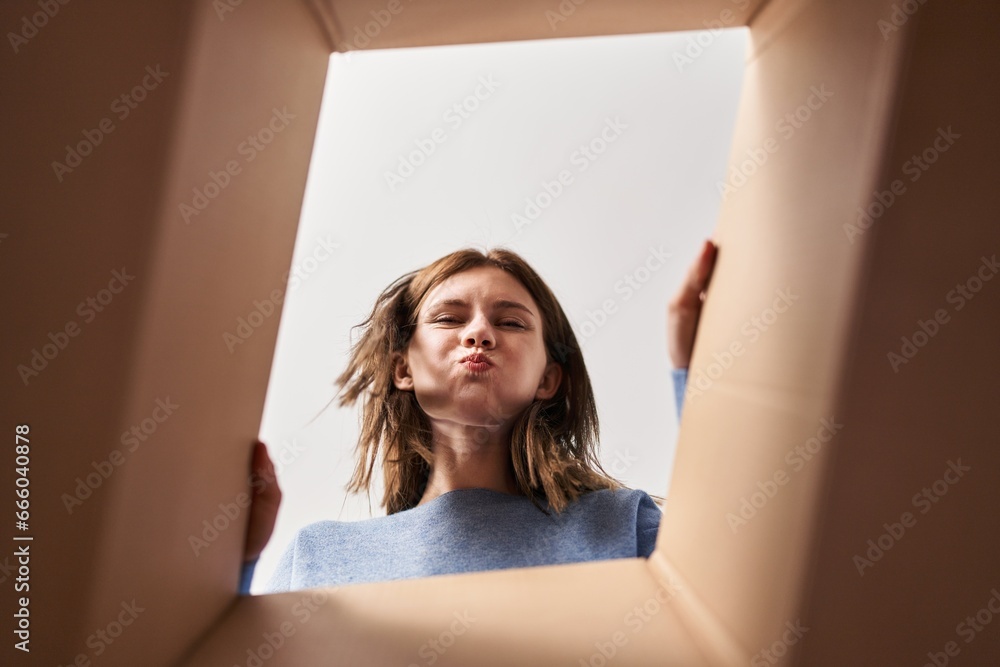 Poster Beautiful woman opening cardboard box puffing cheeks with funny ...