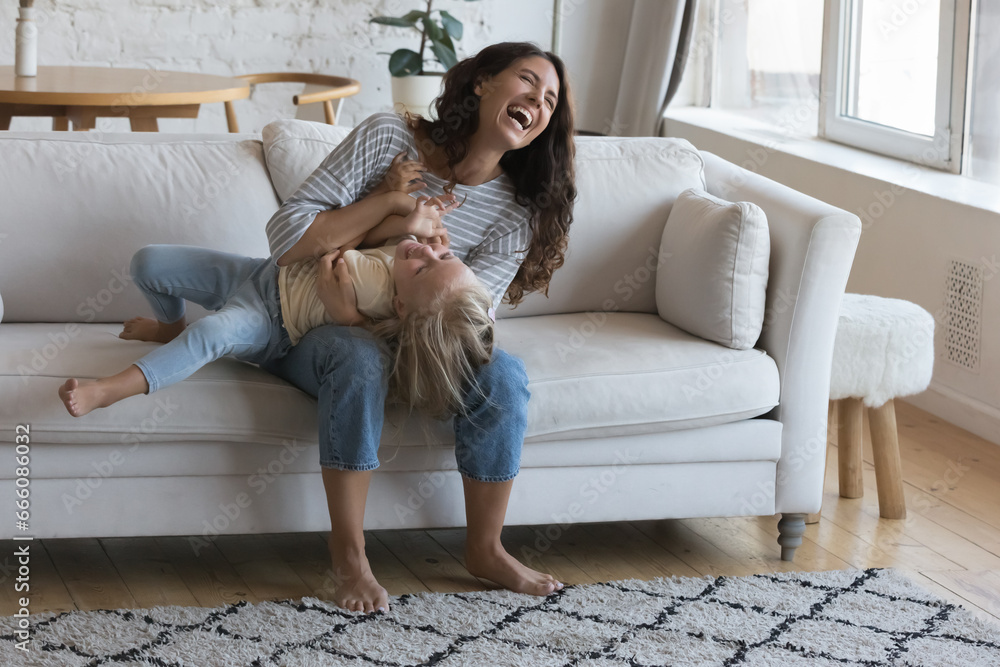Excited joyful mother playing with happy active little daughter ...