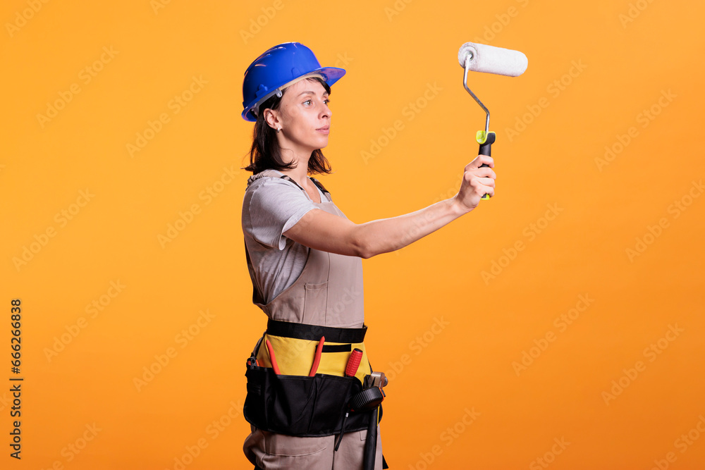 Young constructor holding paintbrush roller and painting walls in ...