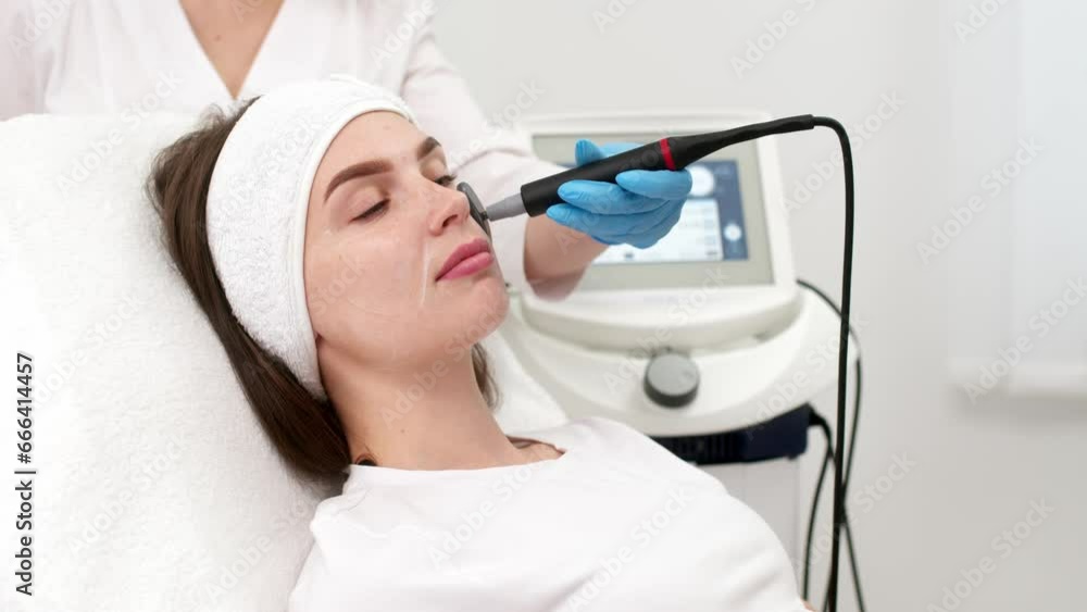 Close-up of a young woman's face during microcurrent therapy. Procedure ...