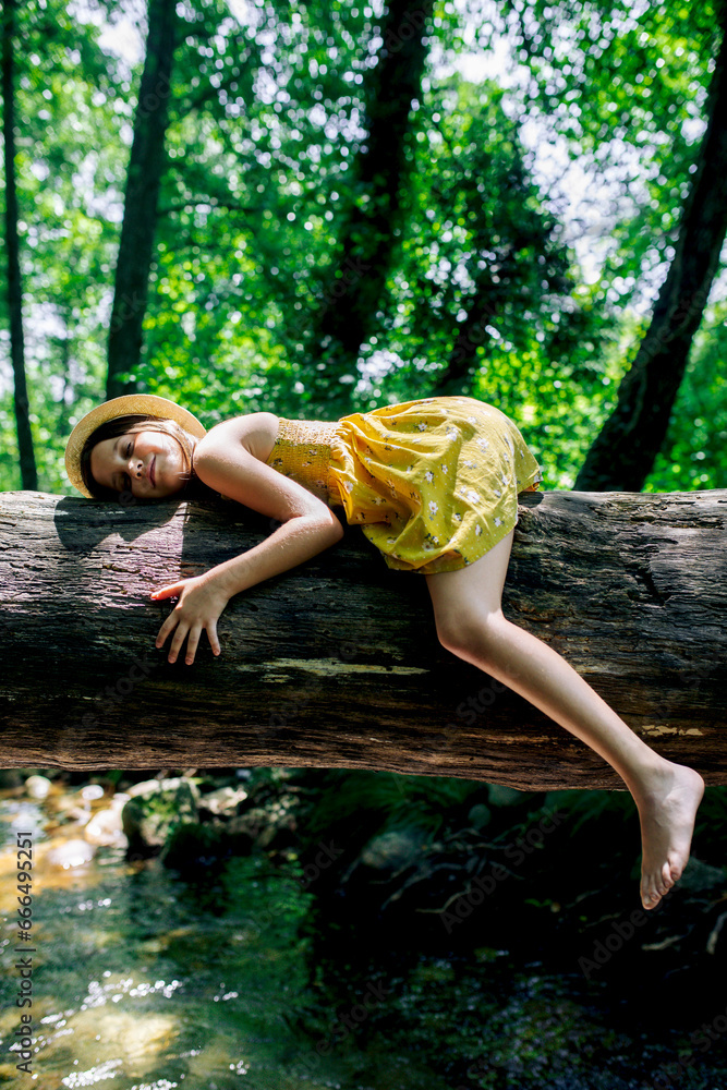 Preteen girl lying on tree trunk in nature Stock Photo | Adobe Stock