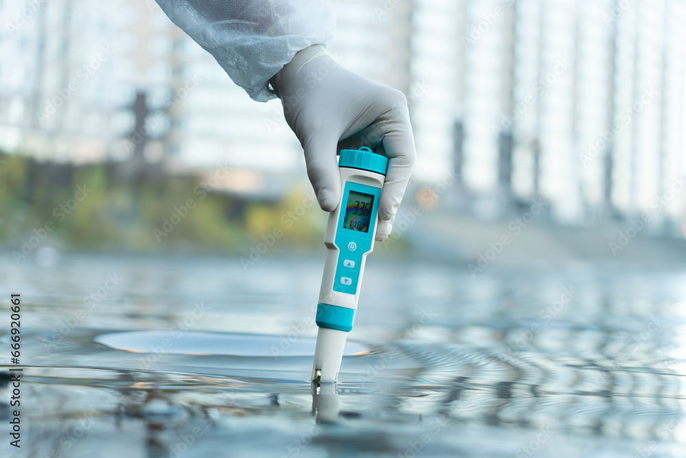 Electronic water testing hand over blurred blue water background, water ...