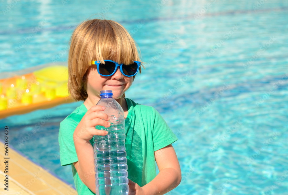 Cute little boy drinks water from a plastic bottle against the ...