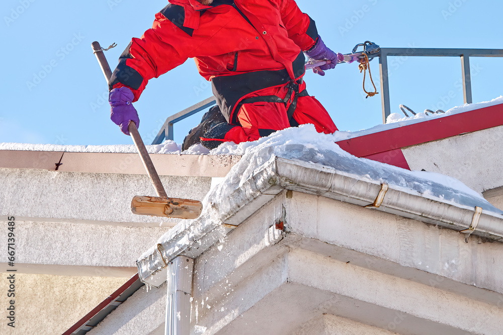 Man breaking ice, knock icicles, clean snowy rooftop. Industrial ...