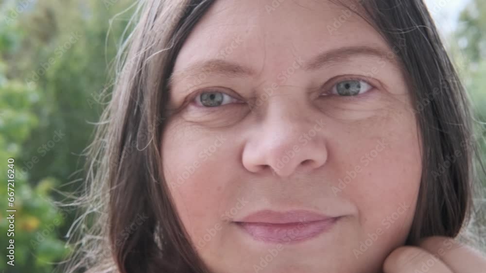 close up of mature female face, woman 50 years old carefully examines ...