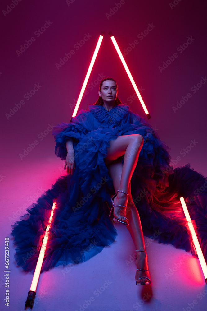 Beautiful model in a lavish blue carnival gown poses in a warmly lit ...