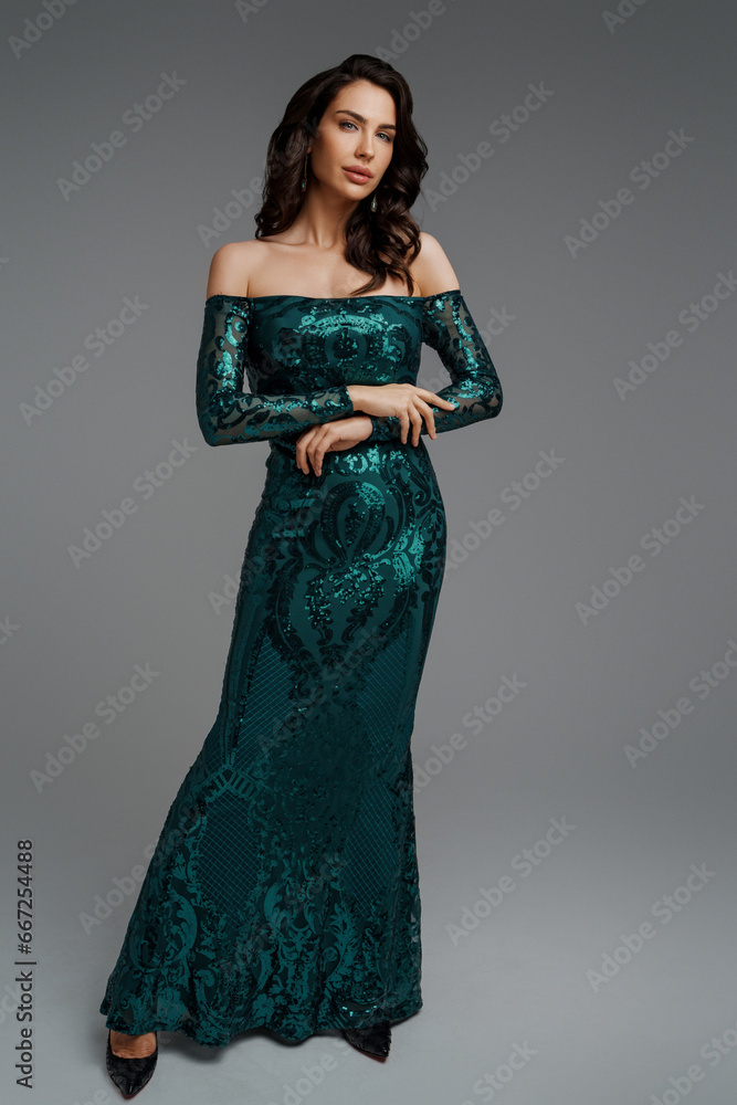 Full-length portrait of a model-esque brunette with voluminous hairstyle in a graceful green ...