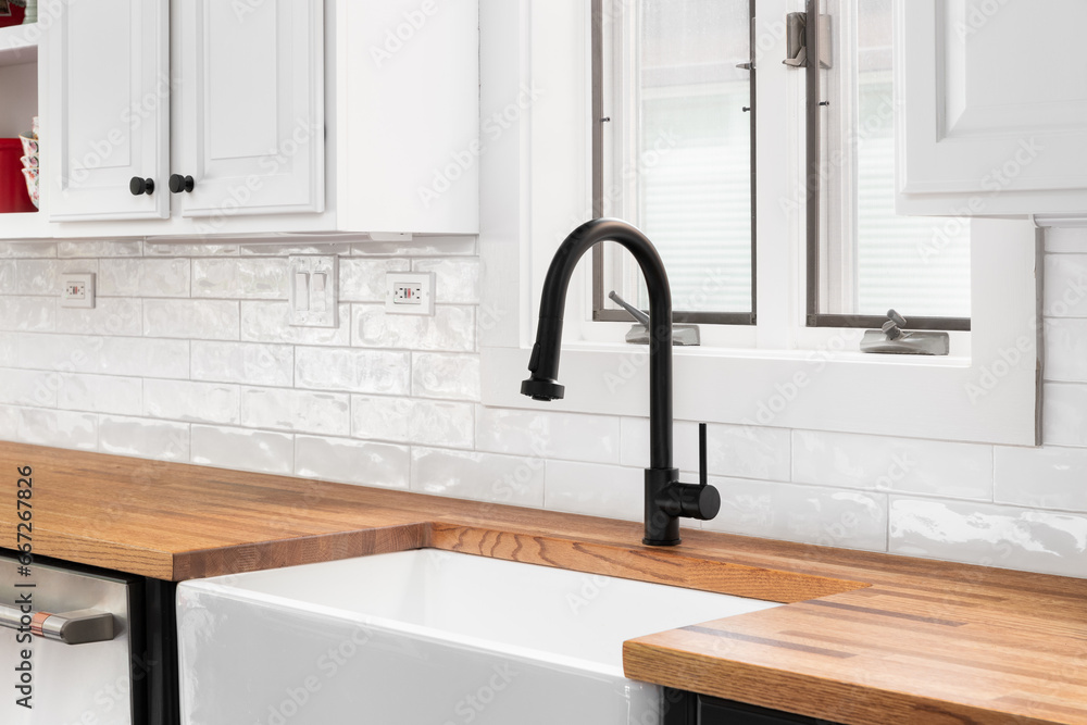A kitchen faucet detail with white cabinets, a butcher block countertop ...