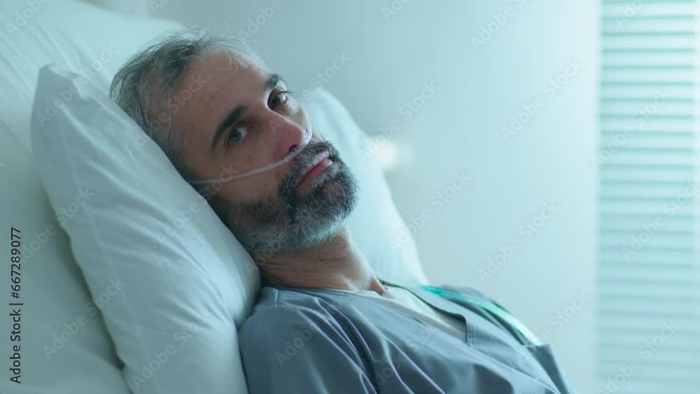 Sick mature male patient with nasal cannula lying on bed in a hospital ...