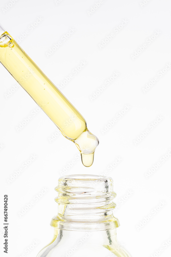 Cosmetic pipette with yellow oily drop close up on white background ...