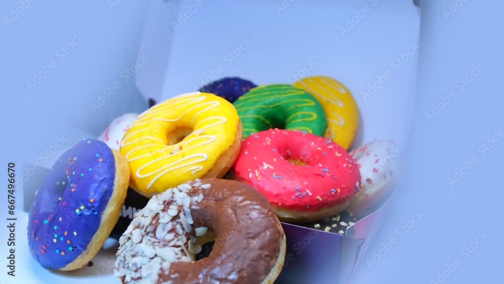Many delicious multi-colored donuts falling out of a filled box on a ...