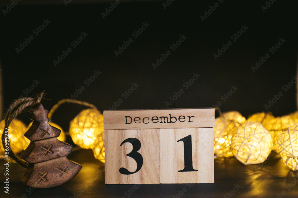 Brown wooden calendar on the black table with New Years garland. Black ...