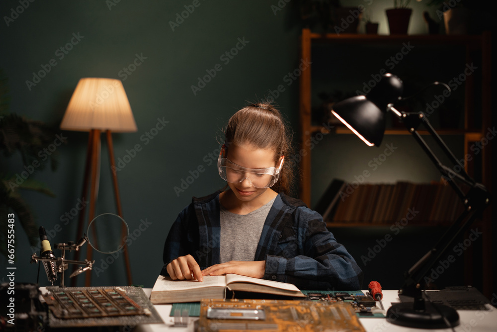 An inquisitive schoolgirl repairing computer motherboard at home while ...