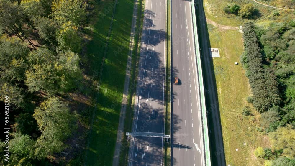 Aerial view of a highway with adjacent lush greenery, casting long ...