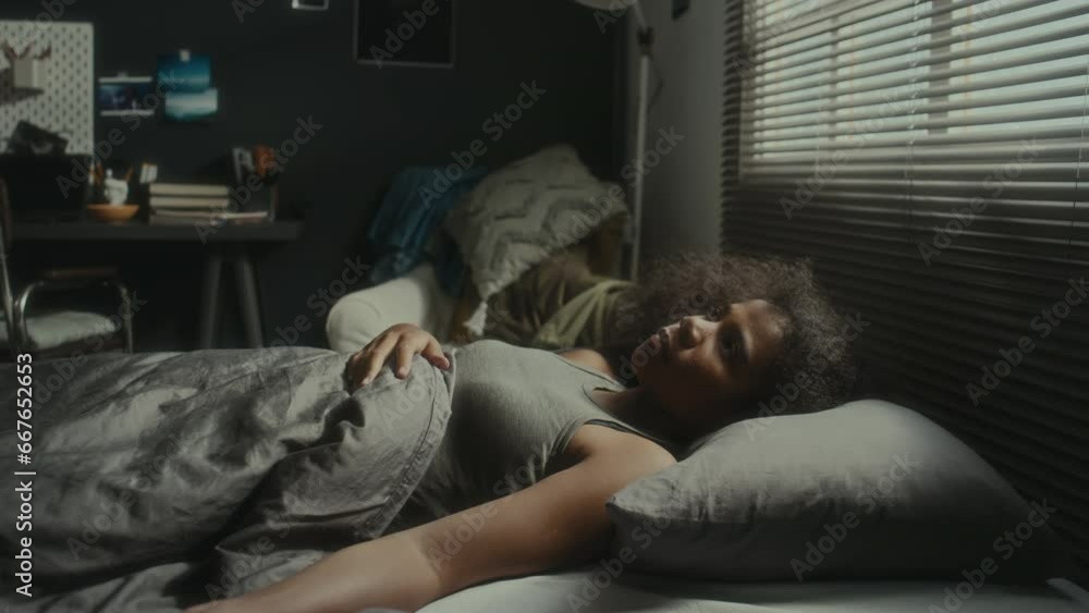Depressed African American teen girl lying in her bed at night and ...