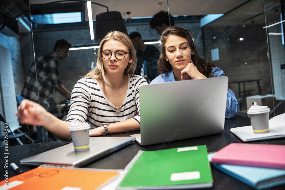 Two Female Programmers And Engineers Work Alongside Their Colleagues In An Office Collaborating