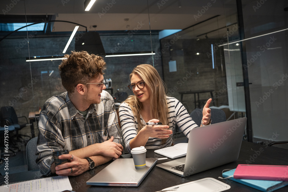 Programmers work alongside their colleagues in an office, collaborating ...