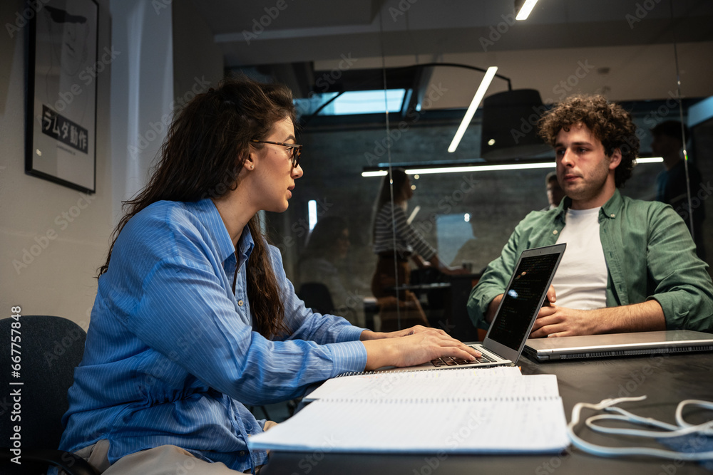 Programmers work alongside their colleagues in an office, collaborating ...