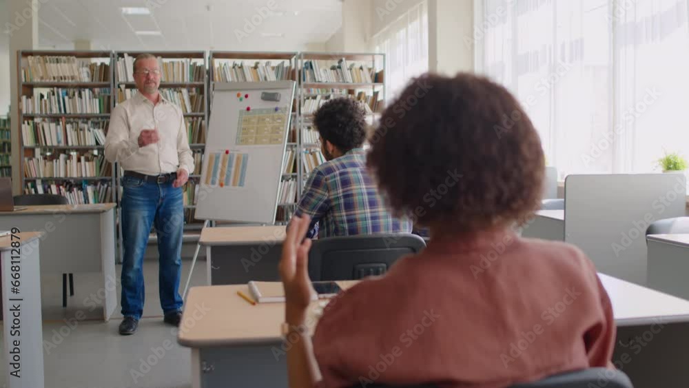 Waist up back view of African American female student raising hand and ...