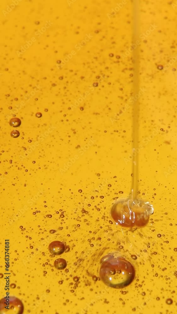 A stream of fresh honey flows down. Liquid honey of golden color flows ...