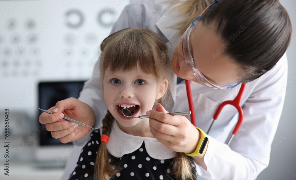 Portrait of cute little girl at stomatologist office. Doctor examining ...