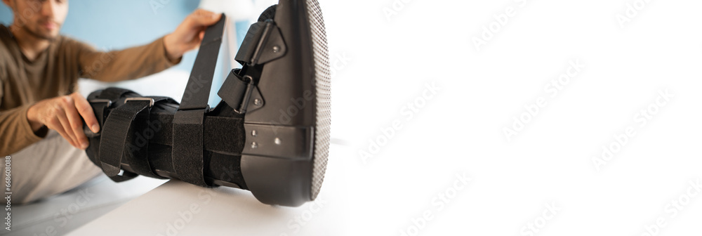Poster Man putting ankle sprain orthosis, black splint on leg sitting ...