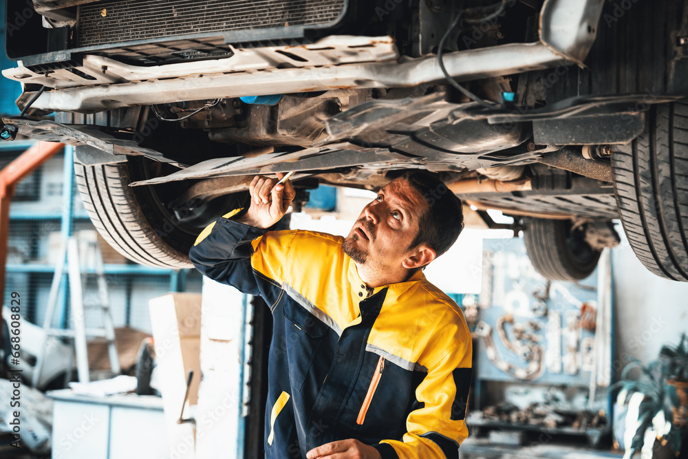 Vehicle mechanic conduct car inspection from beneath lifted vehicle ...