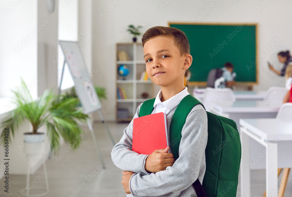 Proud boy first grader with satchel and workbook posing on first day of ...