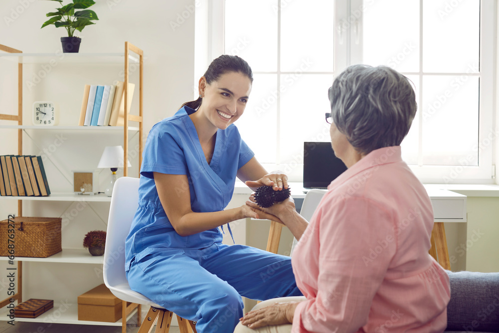 Exercises with spiked ball. Friendly nurse gives elderly woman small ...