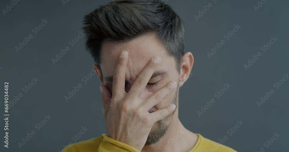 Close-up slow motion portrait of ashamed young man touching face with ...