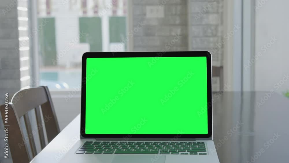 A laptop computer with a key green screen set on work office table ...