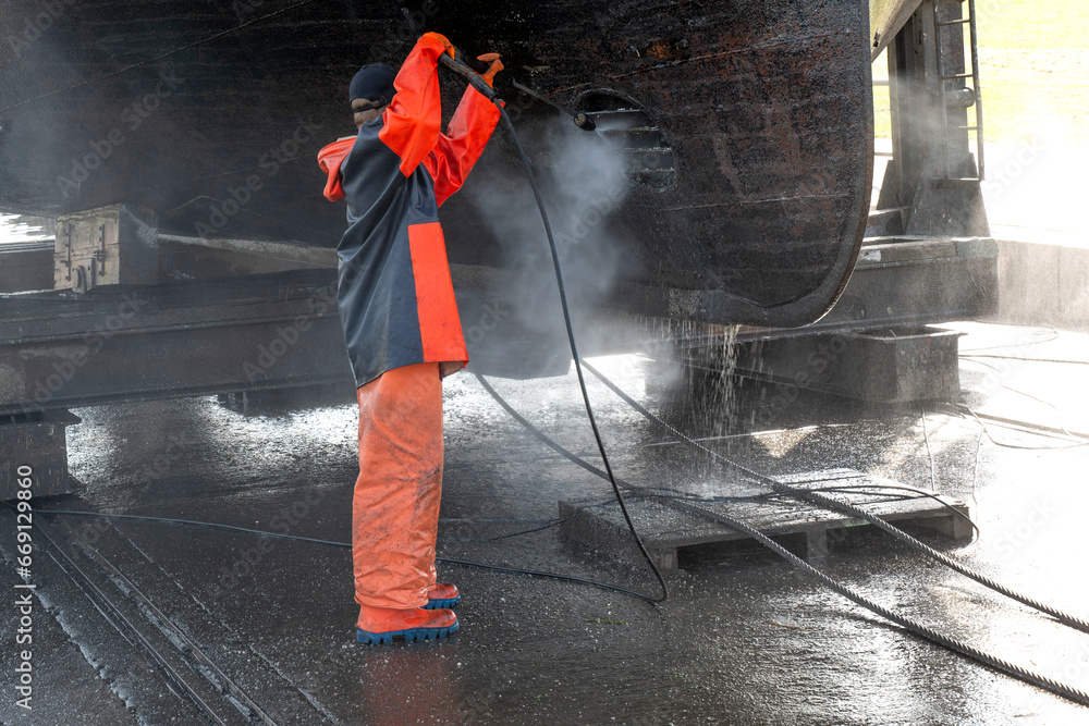 cleaning a ship in the dry dock, cleaning the hull with a high-pressure ...