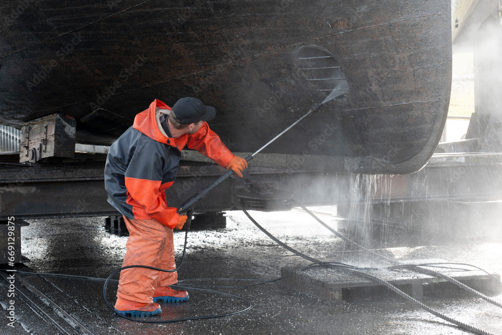 cleaning a ship in the dry dock, cleaning the hull with a high-pressure ...