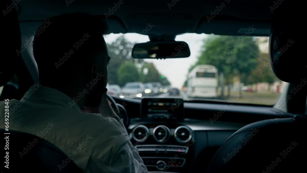 back view a man a businessman is driving a luxury car around the city a ...
