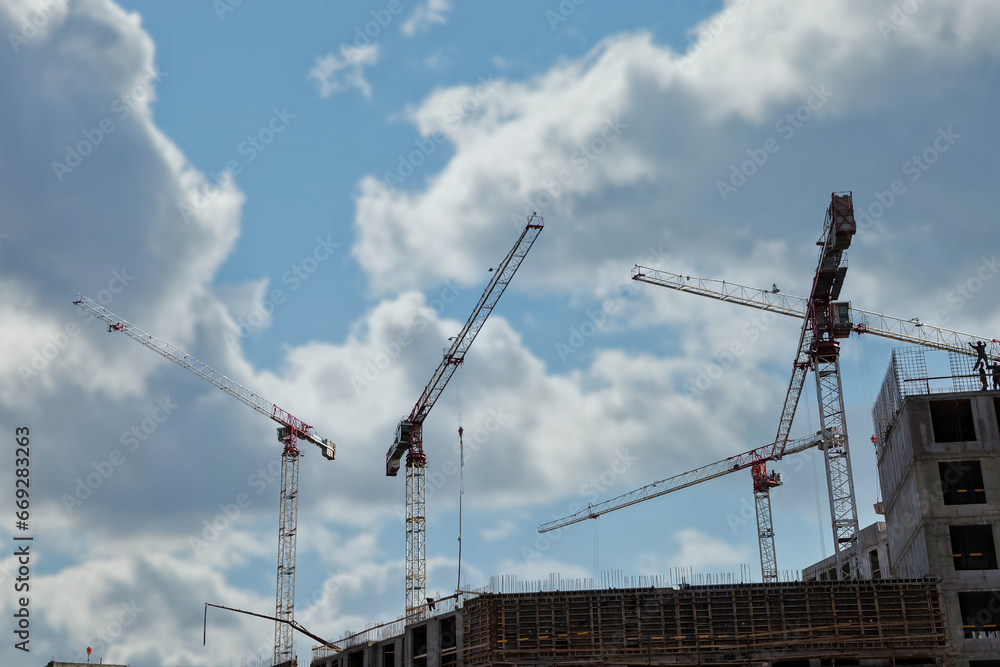 Construction cranes work on creation site against blue sky background ...