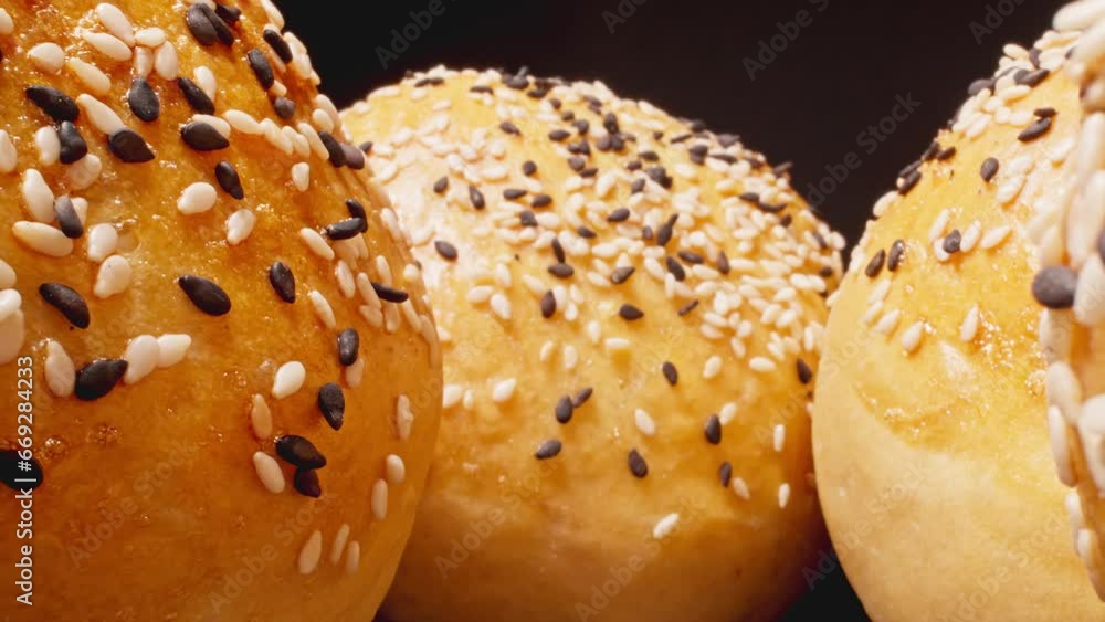 Hamburger buns. Camera moving through row of fresh buns with sesame ...