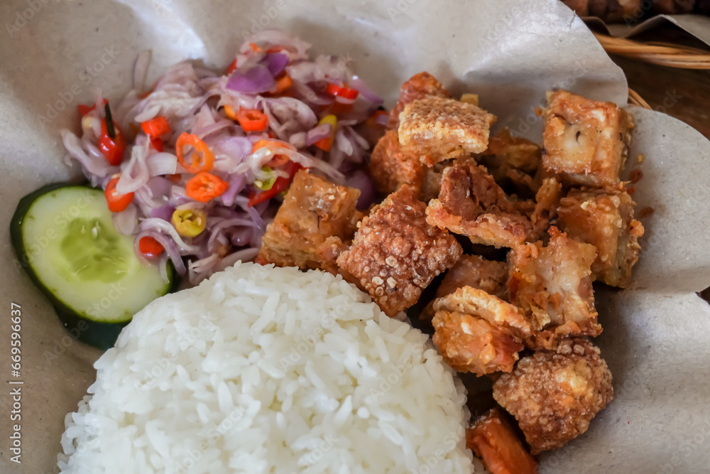 Crispy fried pork served with white rice, sambal matah and sliced ...