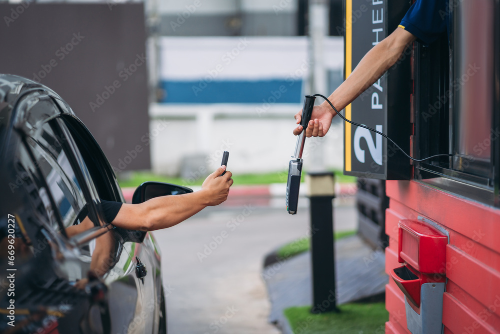 Young Man Pay for food or drinks via mobile phone at drive thru counter ...