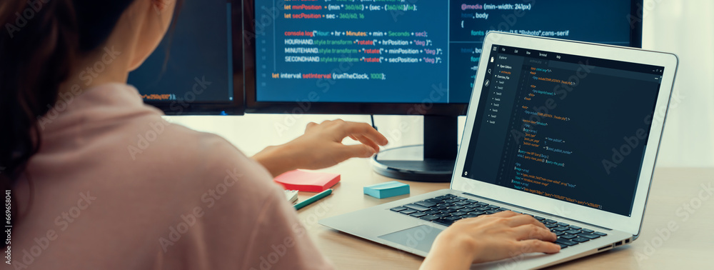 Cropped image of female web developer coding on laptop while computer displayed program and ...