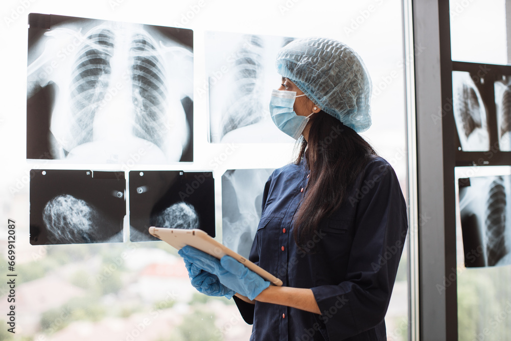 Focused female medical worker in face mask and scrub top posing with ...