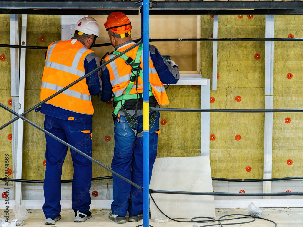 Builders are installing sheathing on walls. Men are finishing facade ...
