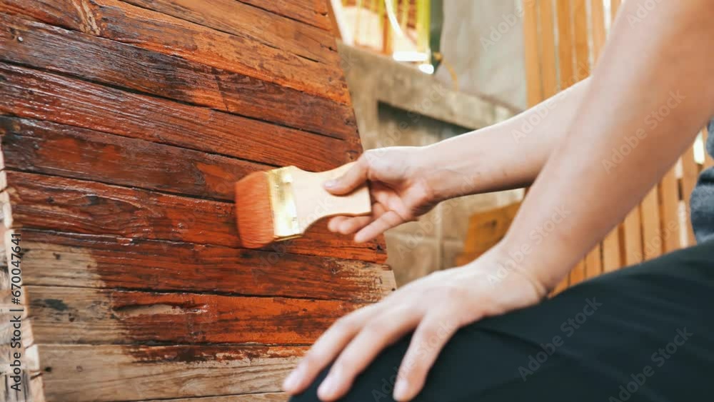 Hand of woman applying wood protection oil on boards with paint brush ...