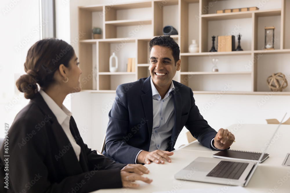 Cheerful manager and client discussing successful cooperation at laptop ...