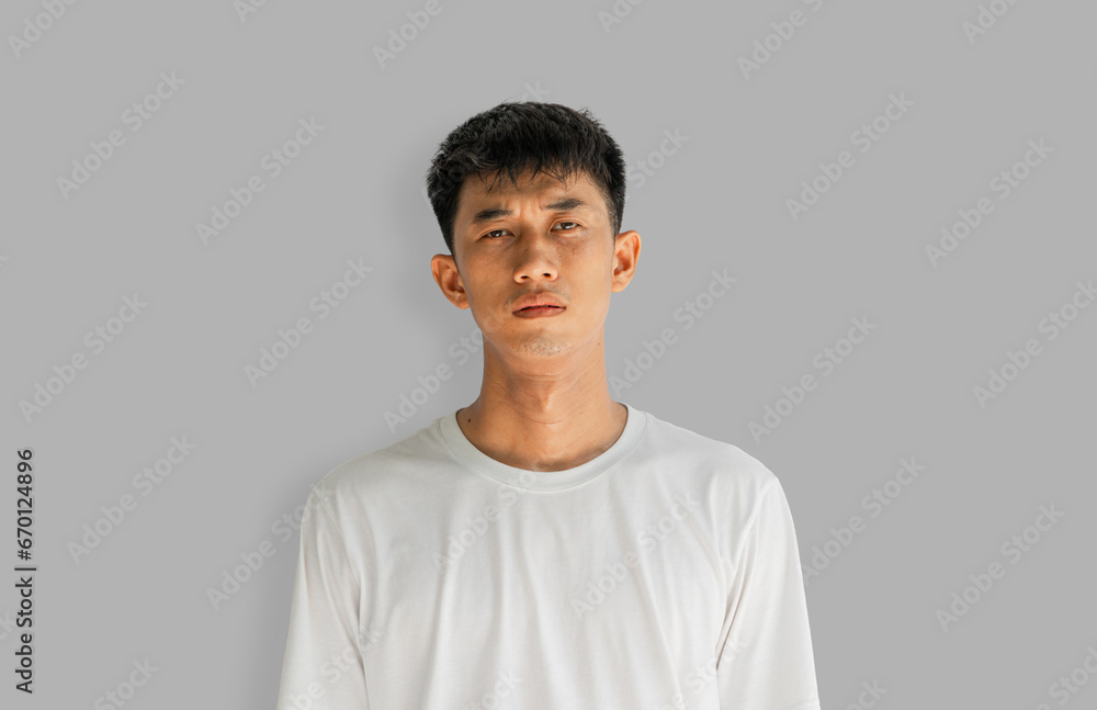 A young Asian man in his 20s wearing a white t-shirt is depressed and ...